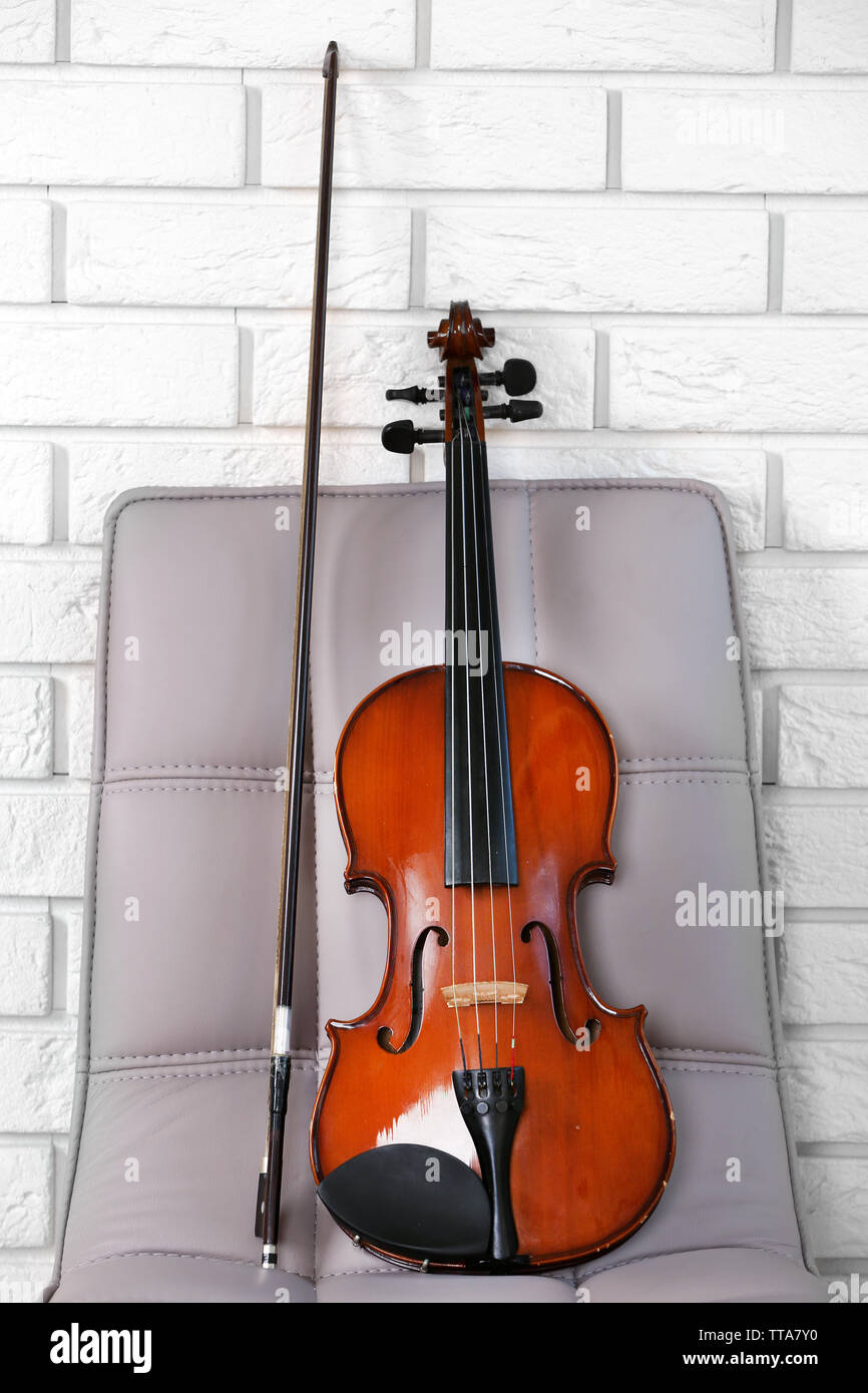Violin on chair, on bricks wall background Stock Photo - Alamy