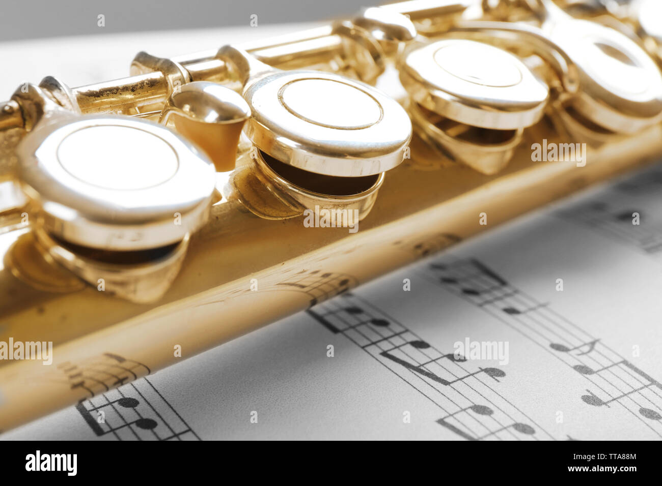 Silver flute on music notes background Stock Photo - Alamy