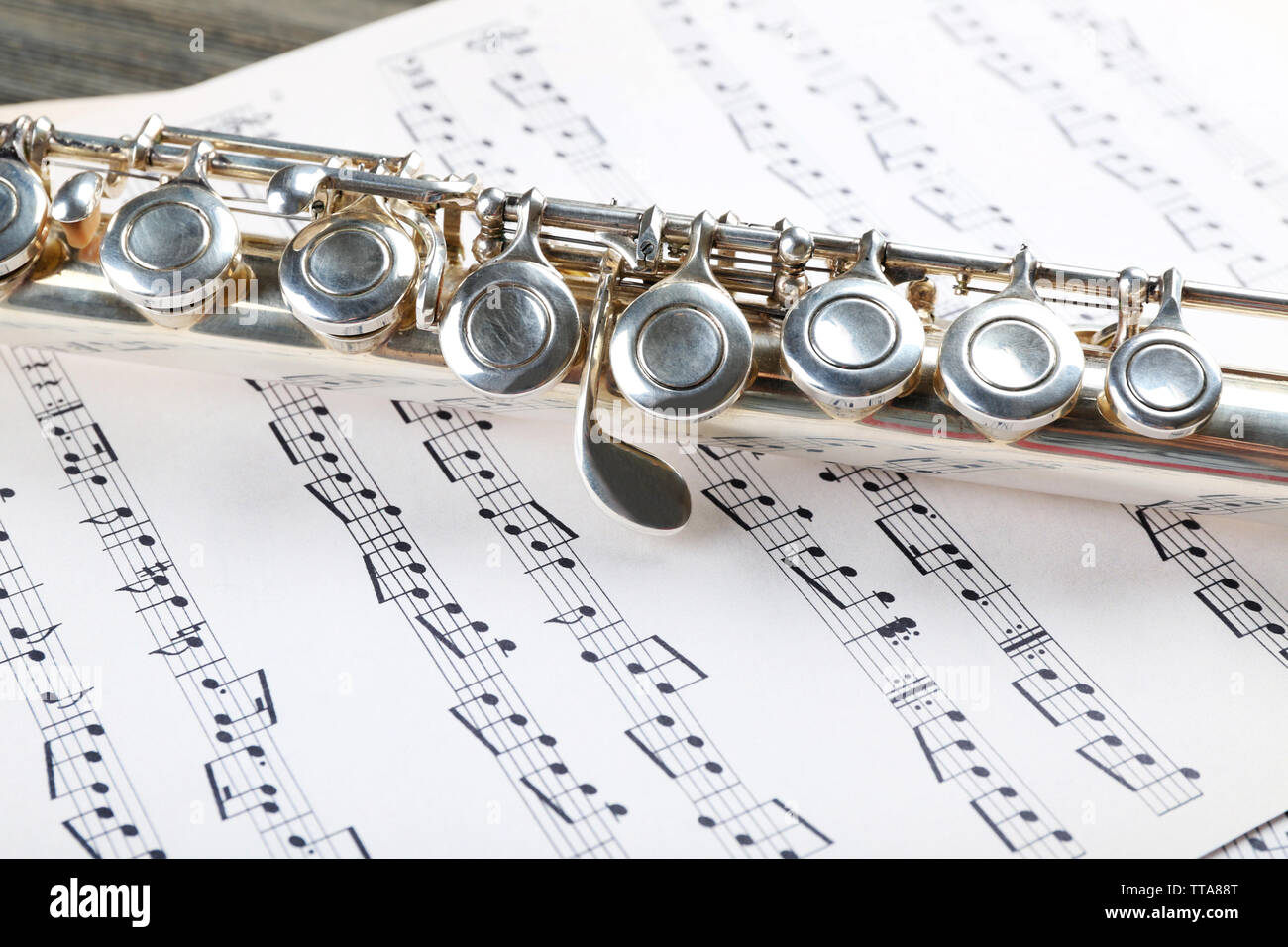 Silver flute on music notes background Stock Photo - Alamy