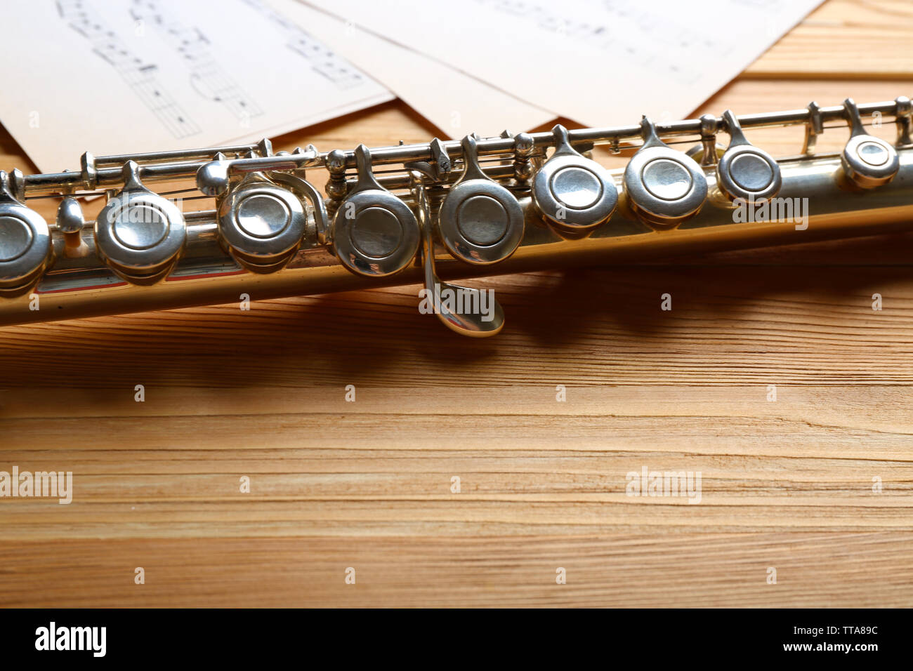 Silver flute with music notes on wooden table close up Stock Photo - Alamy