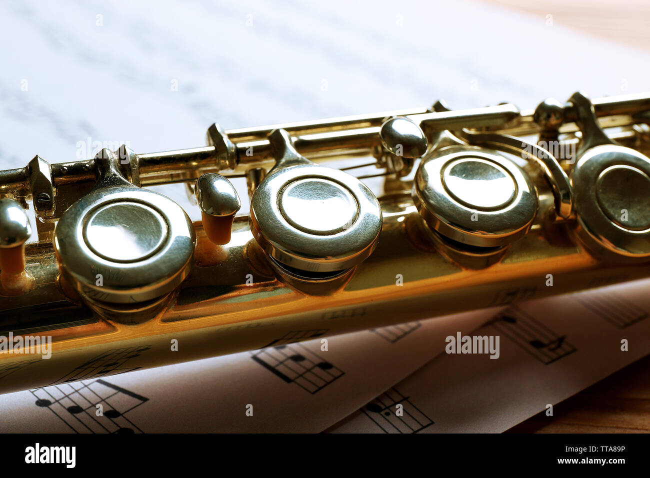 Silver flute on music notes background Stock Photo - Alamy