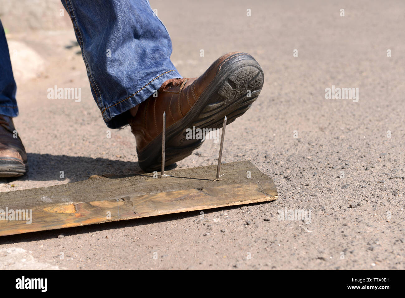 Worker steps on nail outdoors Stock Photo - Alamy