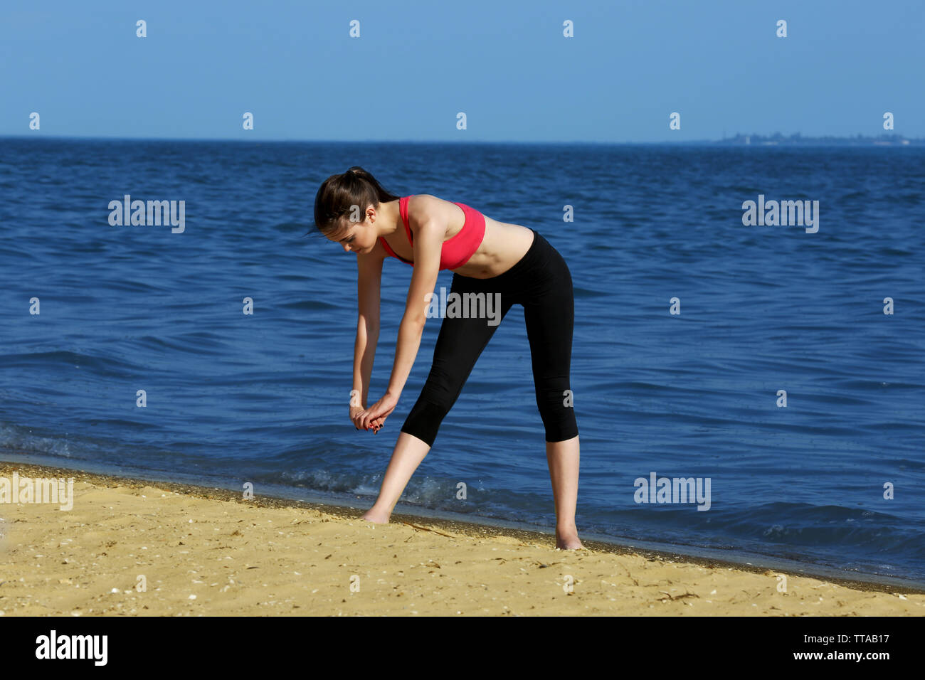 Young sporty woman doing exercise on beach Stock Photo - Alamy