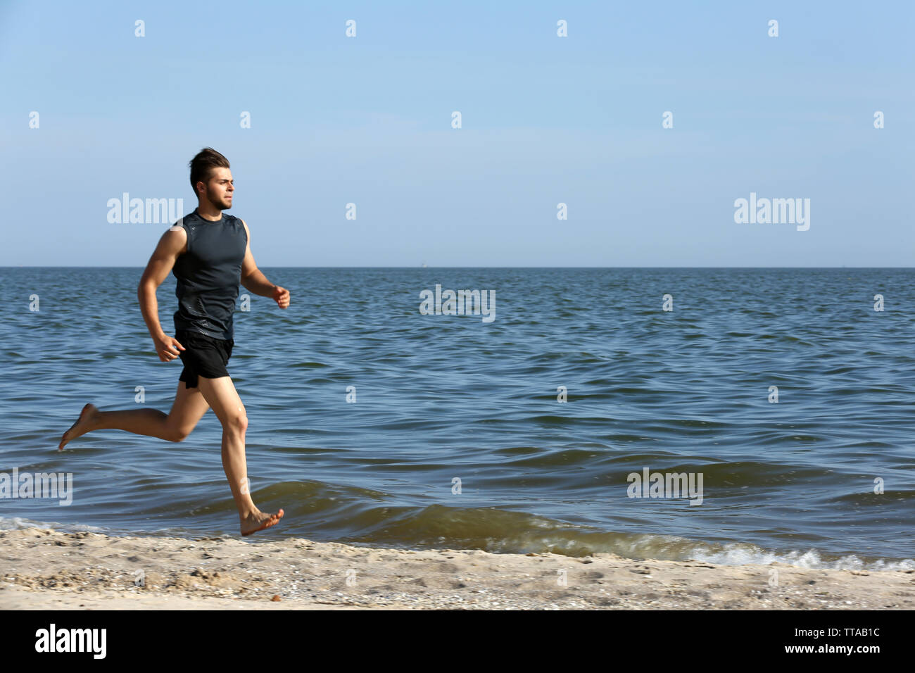 Young man jogging on beach Stock Photo - Alamy