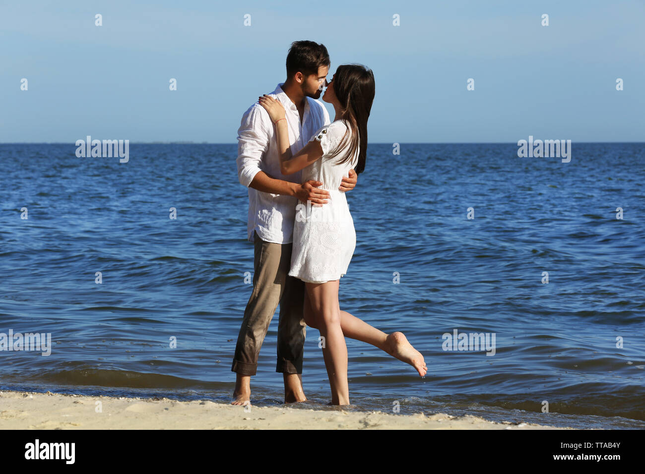 Young couple hugging on beach Stock Photo - Alamy