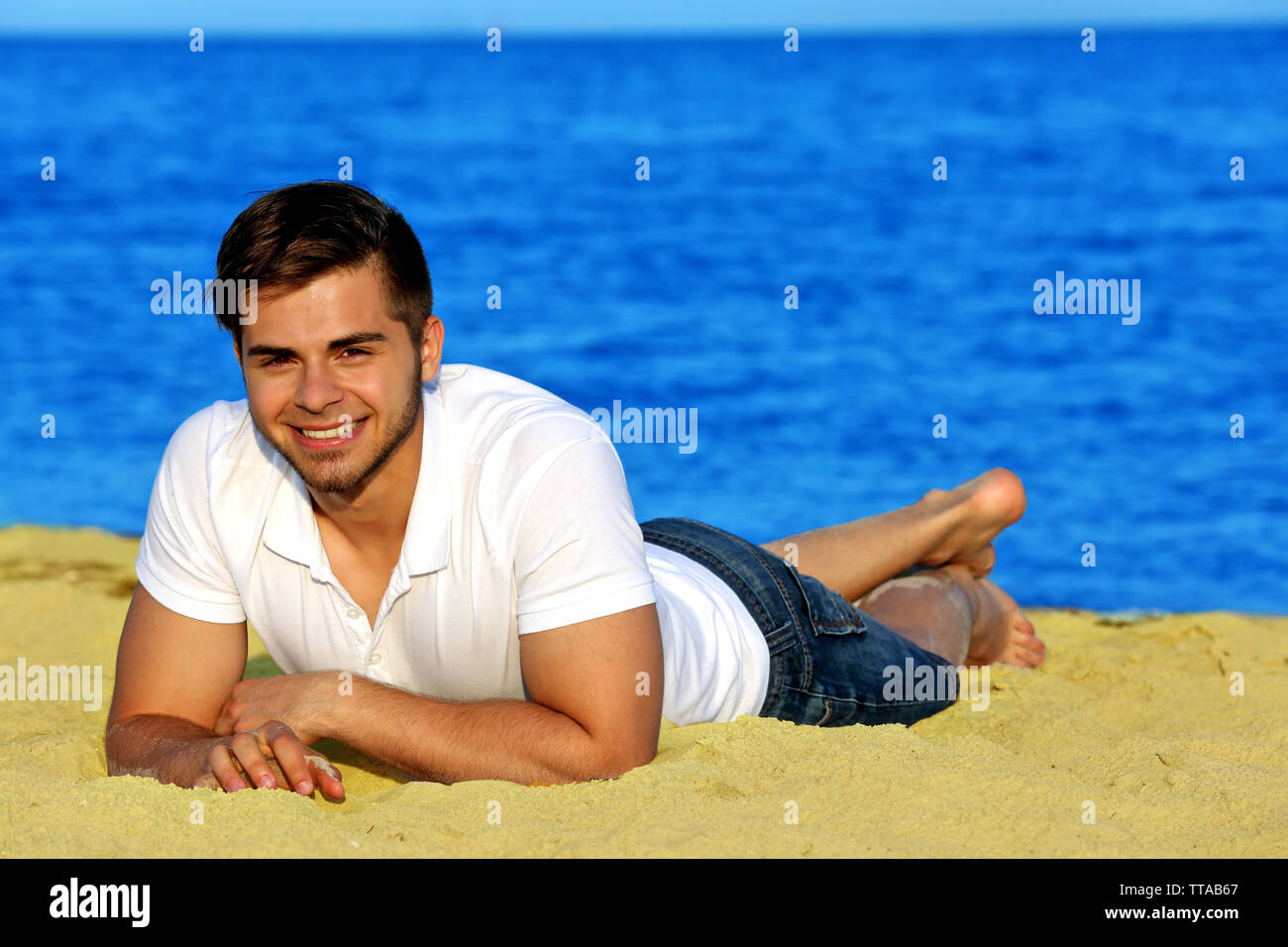 Pretty guy lying on beach Stock Photo - Alamy