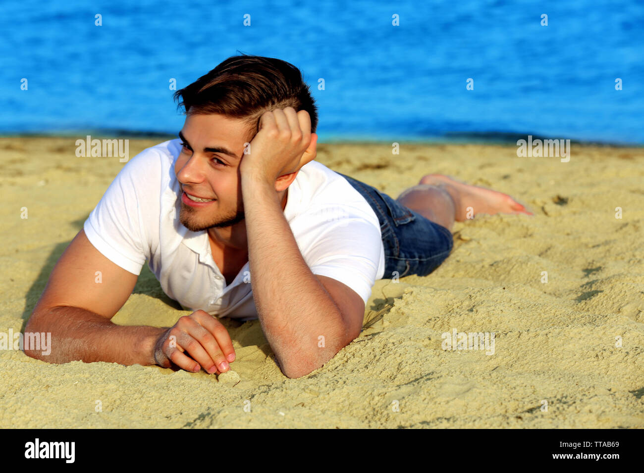 Pretty guy lying on beach Stock Photo - Alamy