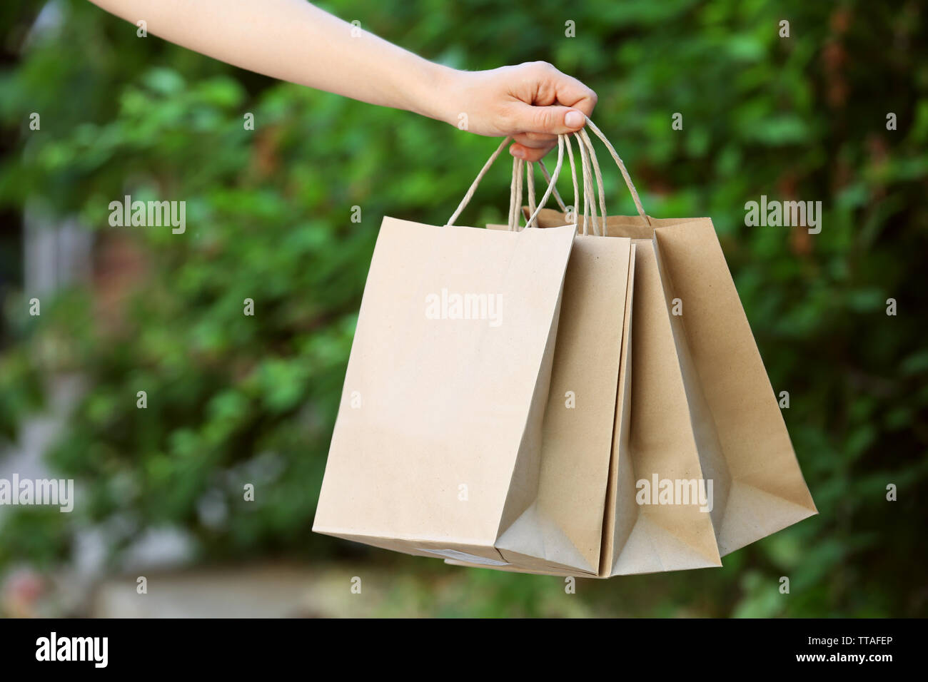 Female hand holding shopping bags outdoors Stock Photo - Alamy