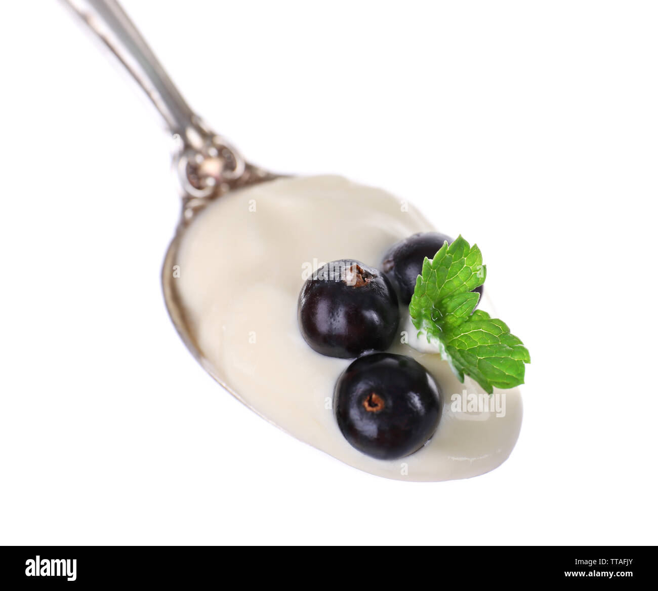 Delicious yogurt in spoon with blackcurrants and mint isolated on white ...