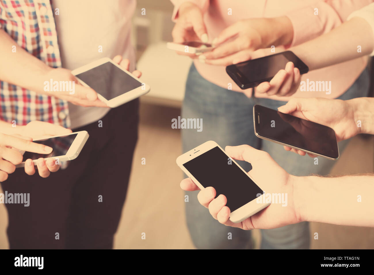 Many hands holding mobile phones close up Stock Photo - Alamy