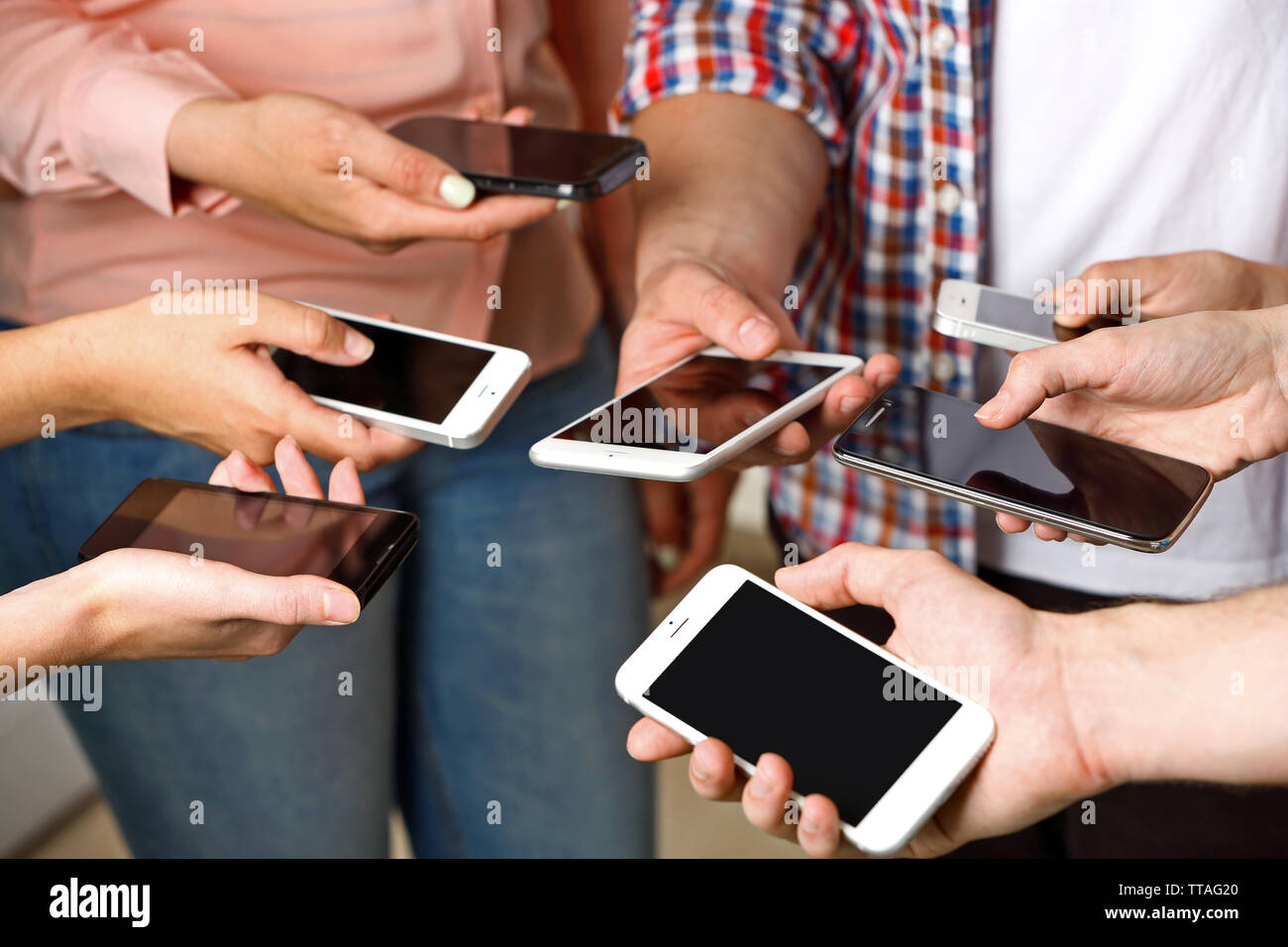 Many hands holding mobile phones close up Stock Photo - Alamy