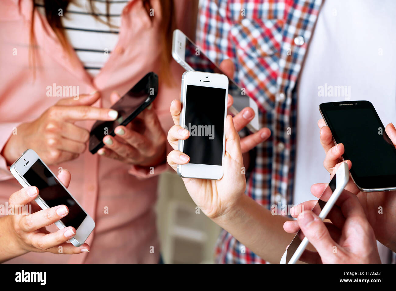 Many hands holding mobile phones close up Stock Photo - Alamy
