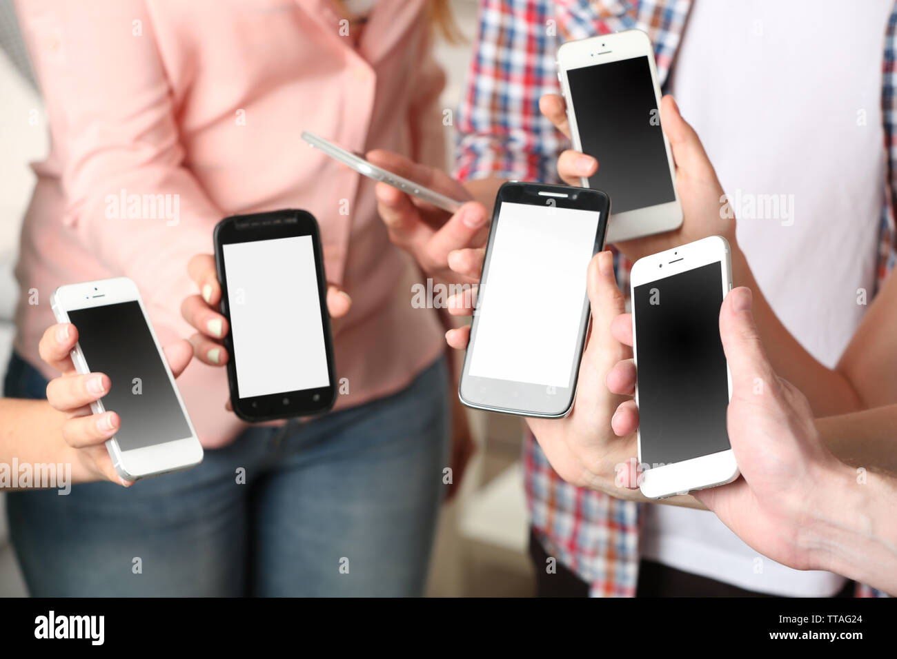 Many hands holding mobile phones close up Stock Photo - Alamy