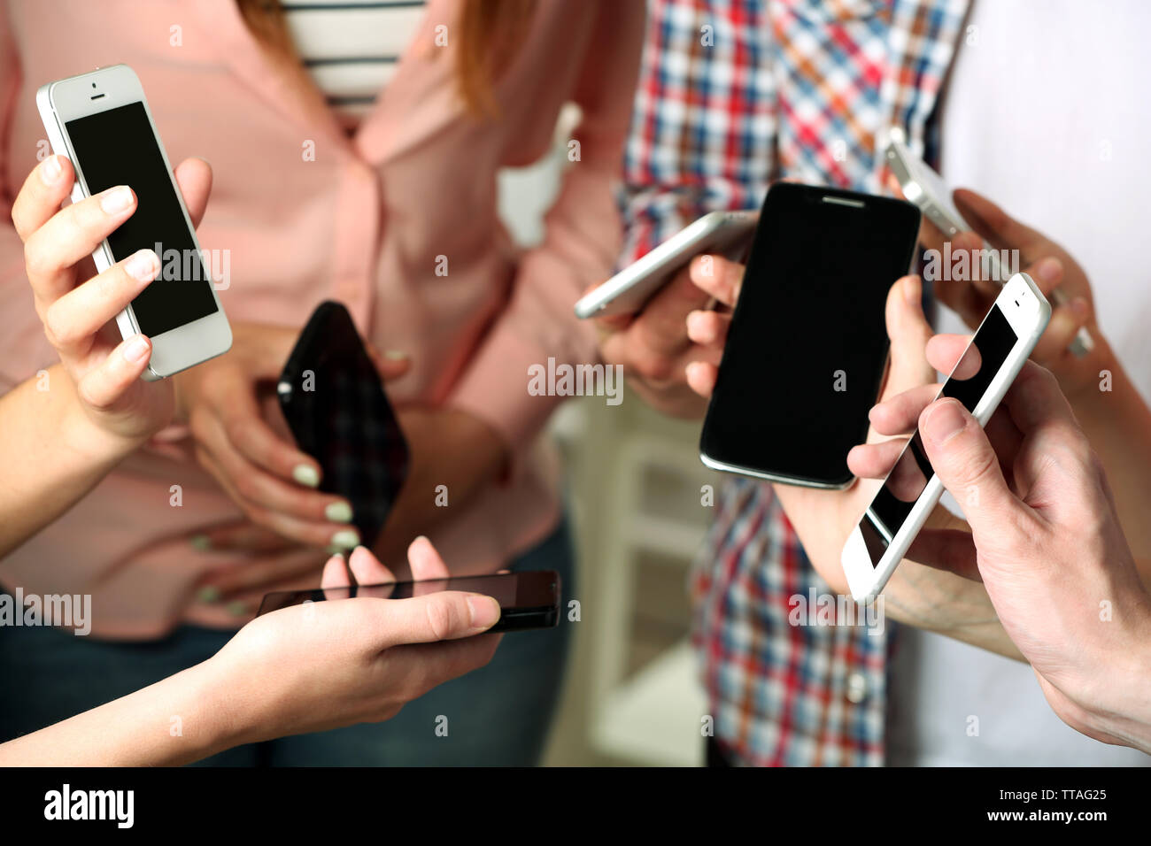 Many hands holding mobile phones close up Stock Photo - Alamy
