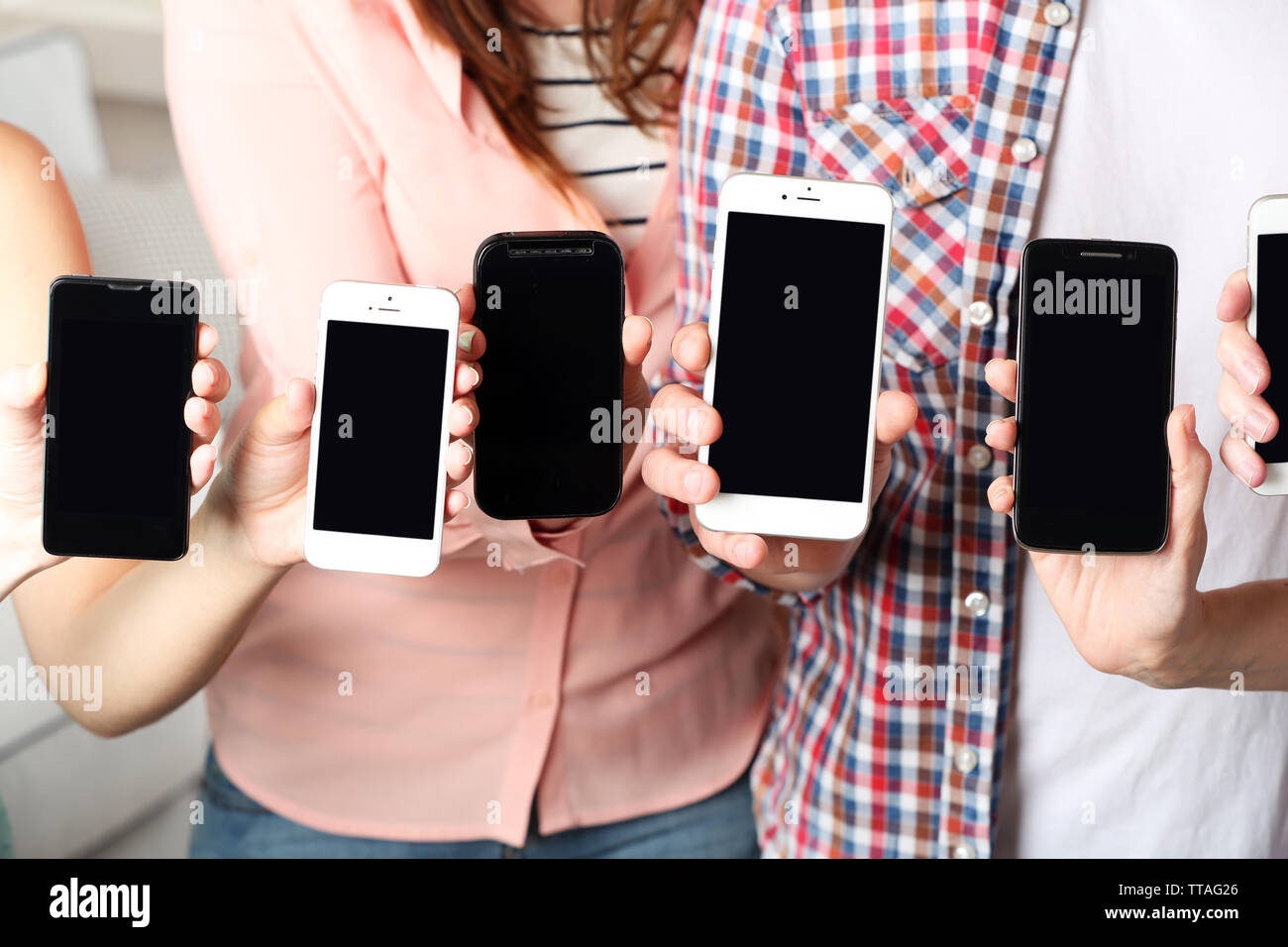Many hands holding mobile phones close up Stock Photo - Alamy