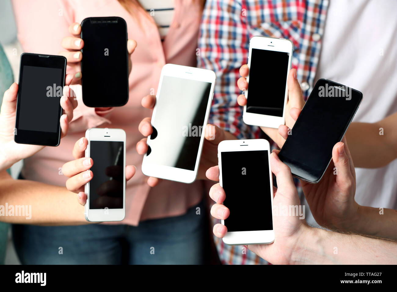 Many hands holding mobile phones close up Stock Photo - Alamy