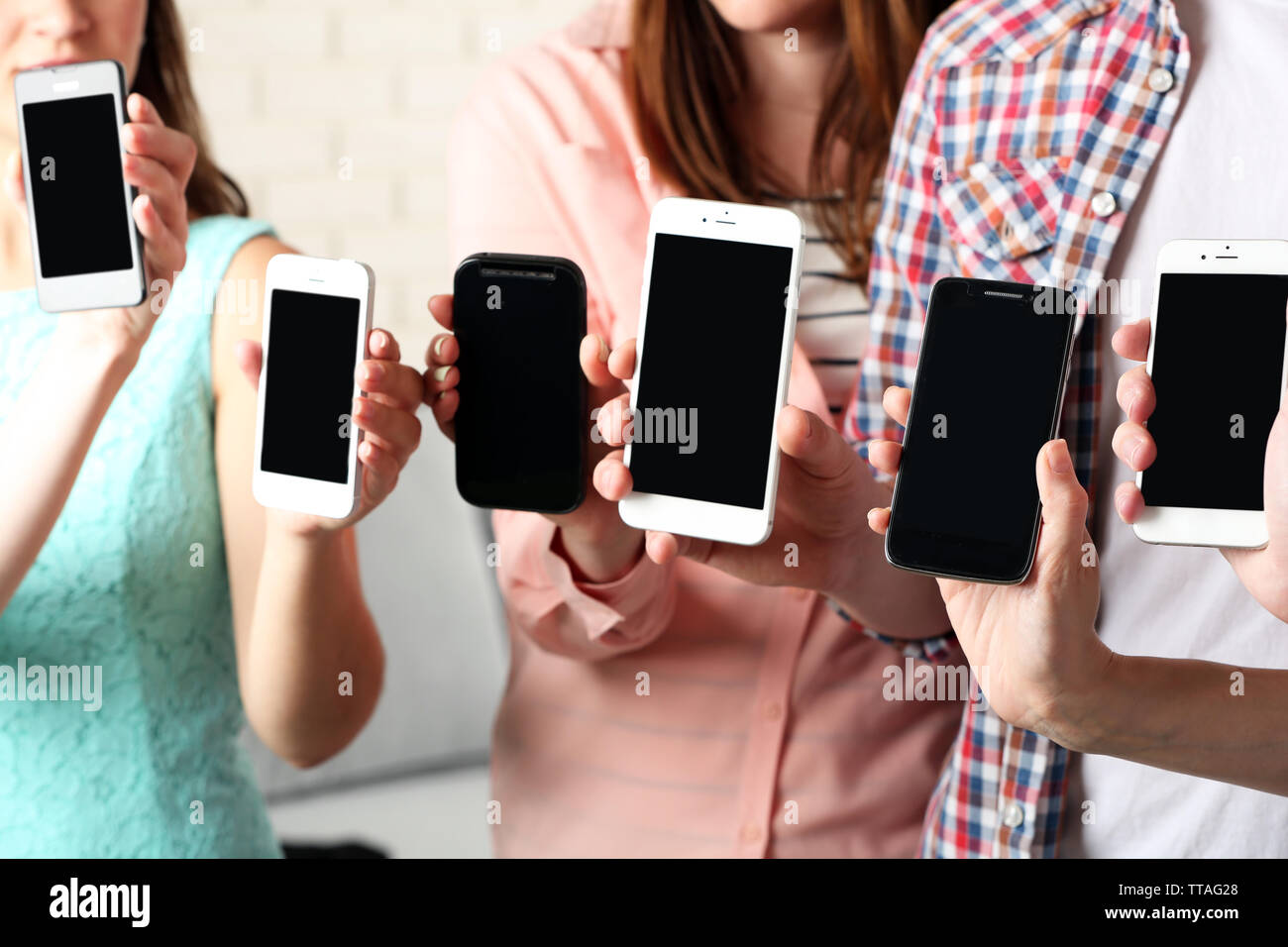 Many hands holding mobile phones close up Stock Photo - Alamy