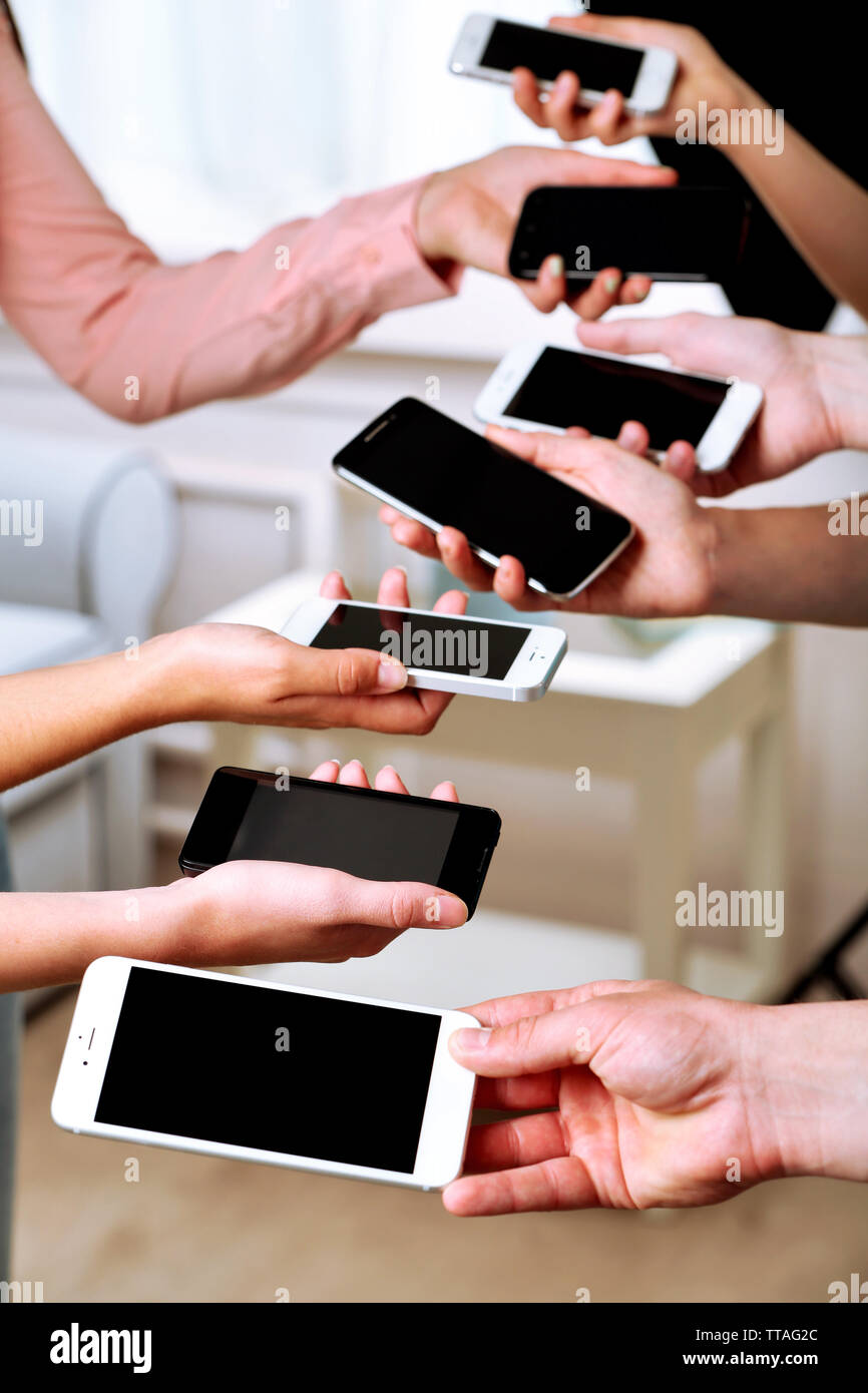 Many hands holding mobile phones close up Stock Photo - Alamy