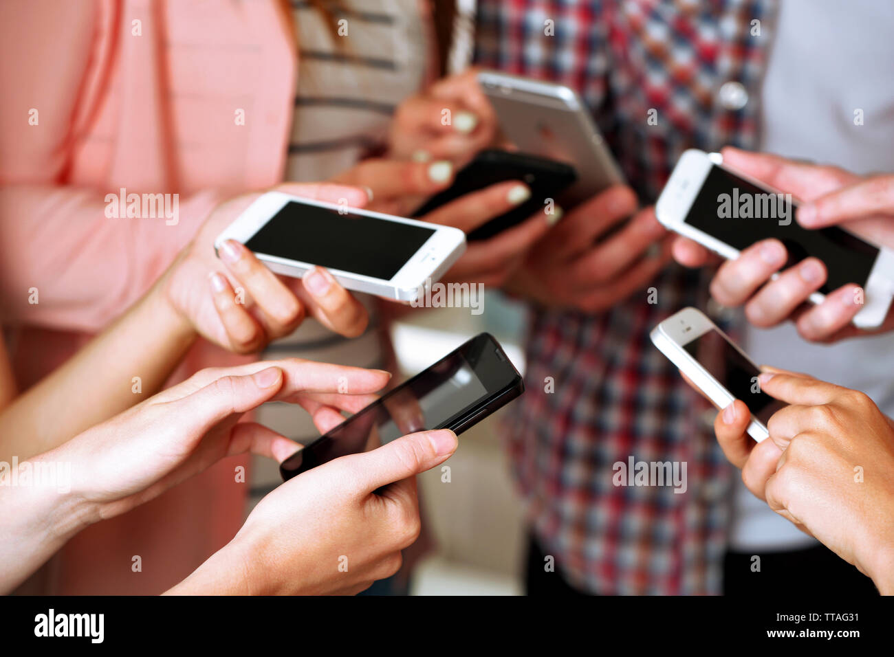 Many hands holding mobile phones close up Stock Photo - Alamy
