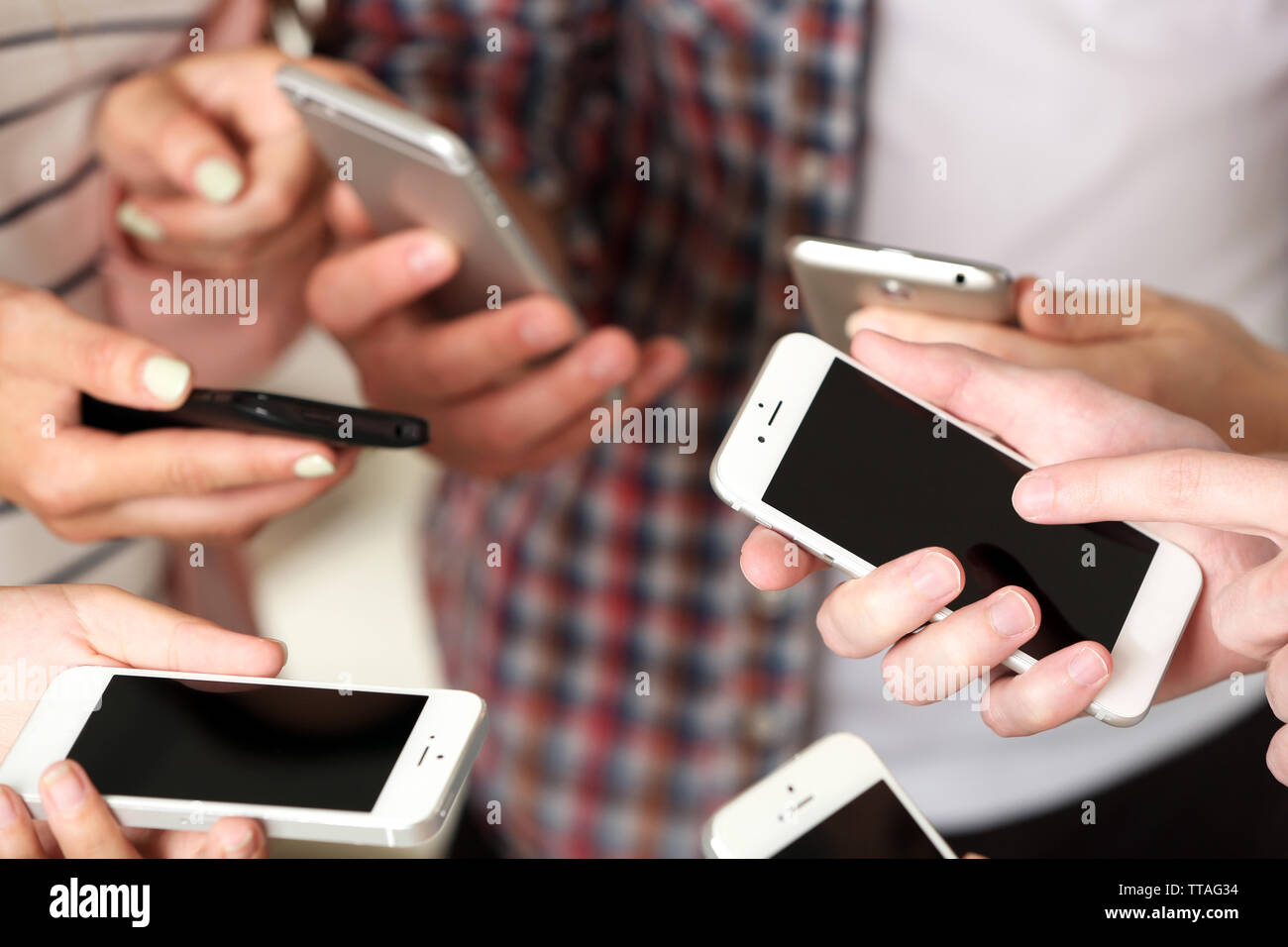 Many hands holding mobile phones close up Stock Photo - Alamy