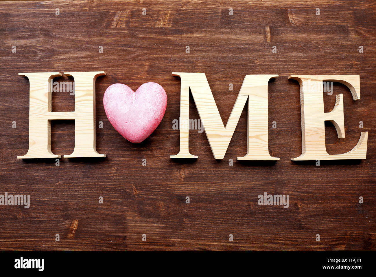 Decorative letters forming word HOME with heart on wooden background ...