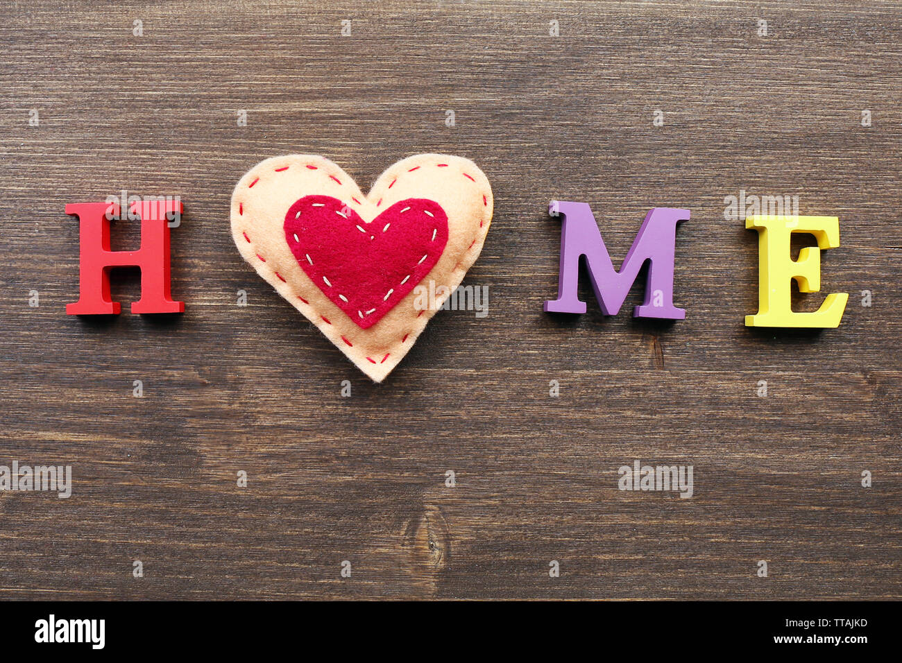 Decorative letters forming word HOME with heart on wooden background ...