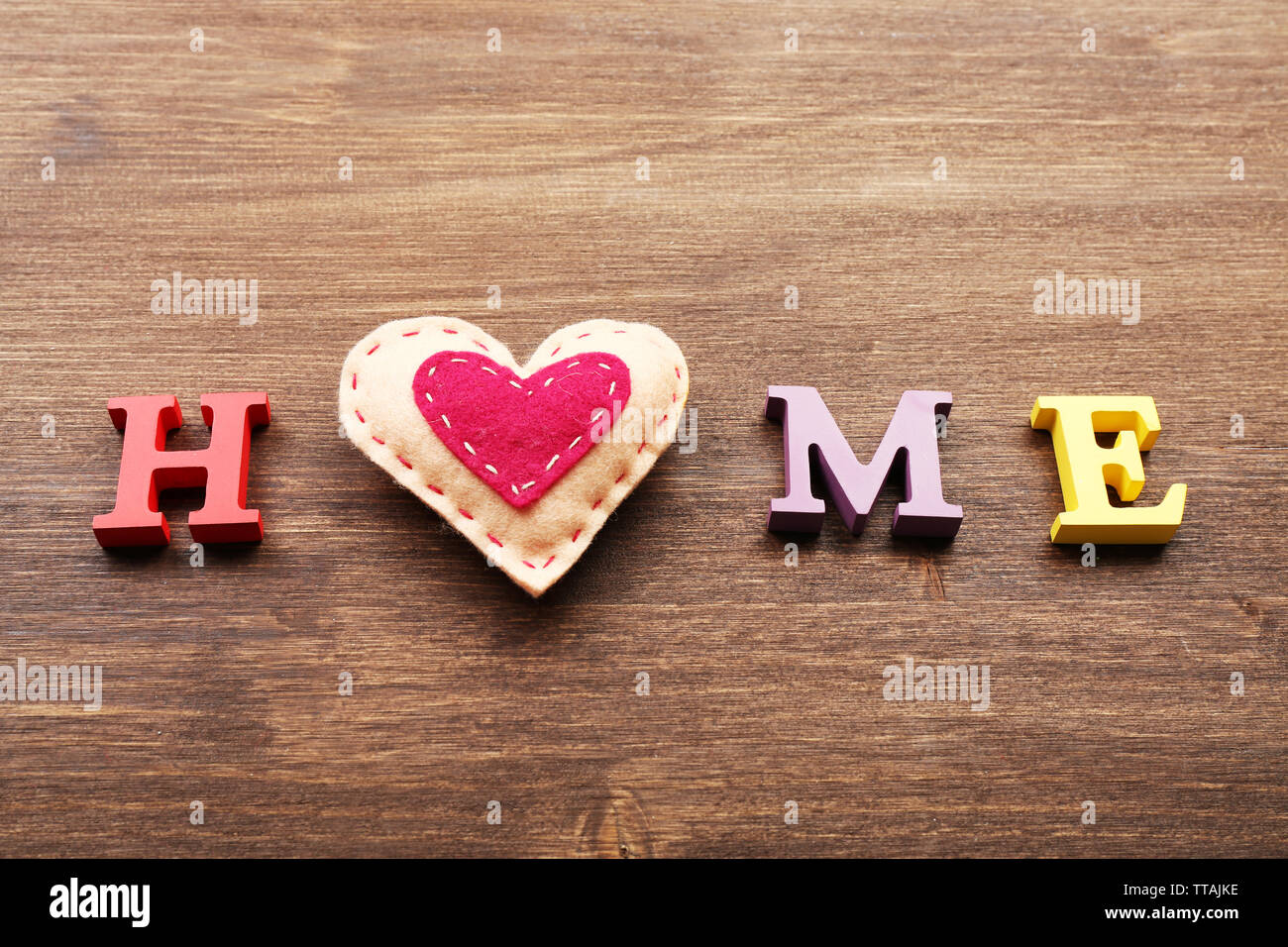 Decorative letters forming word HOME with heart on wooden background ...