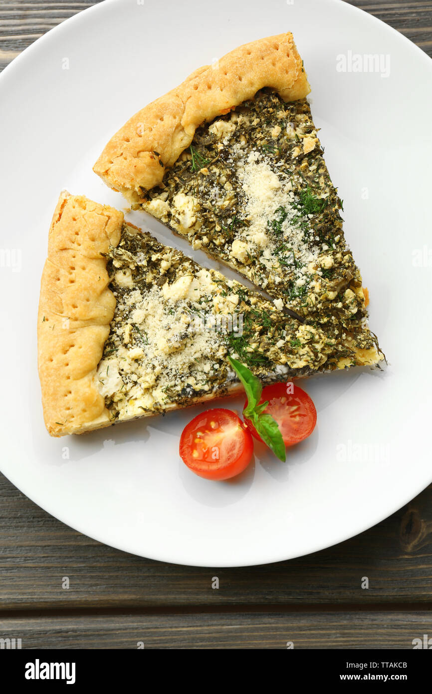 Slices of open pie with spinach and tomato cherry on plate close up ...