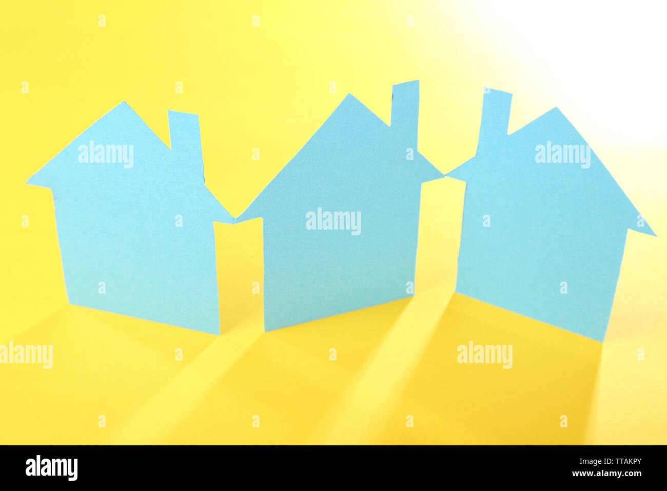 Color paper houses on yellow background Stock Photo - Alamy