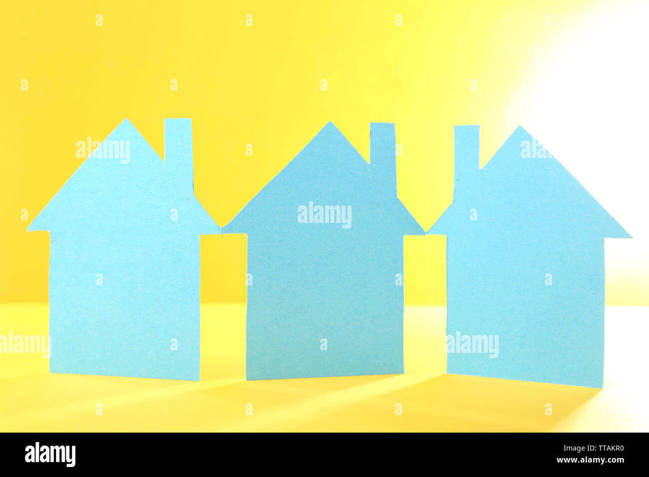 Color paper houses on yellow background Stock Photo - Alamy