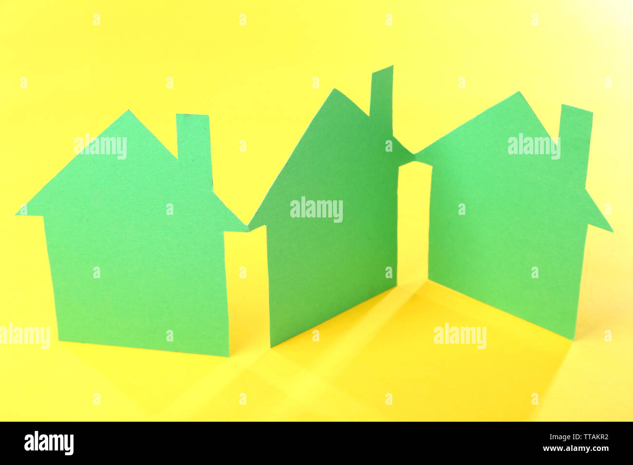 Color paper houses on yellow background Stock Photo - Alamy