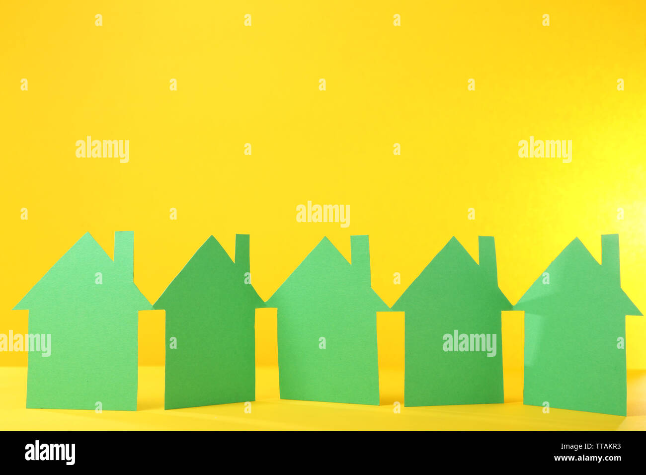 Color paper houses on yellow background Stock Photo - Alamy
