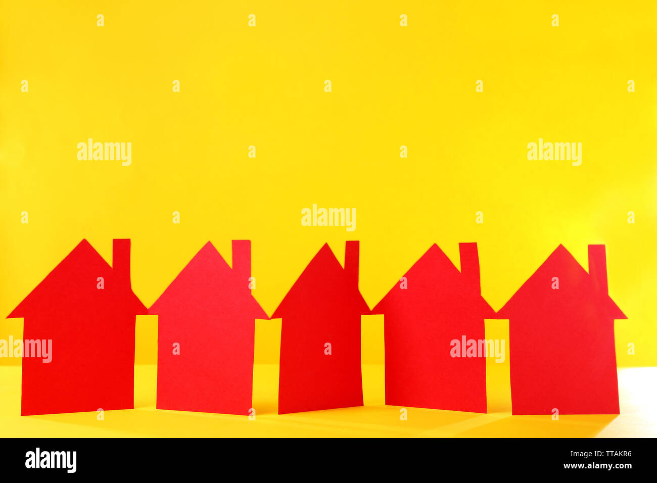 Color paper houses on yellow background Stock Photo - Alamy