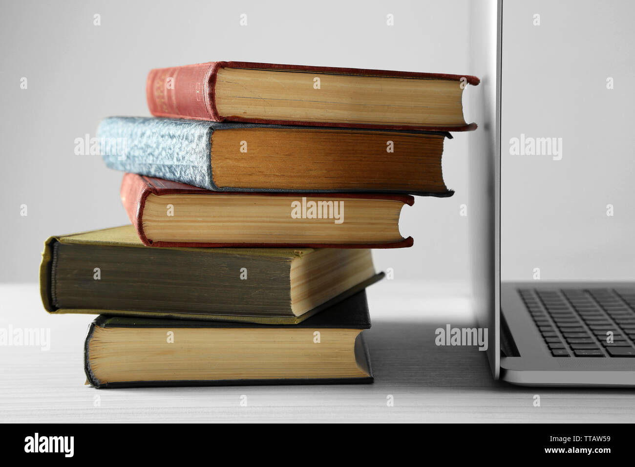 Stack of books with laptop on gray background Stock Photo - Alamy