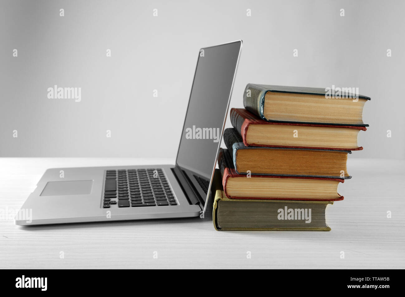 Stack of books with laptop on gray background Stock Photo - Alamy