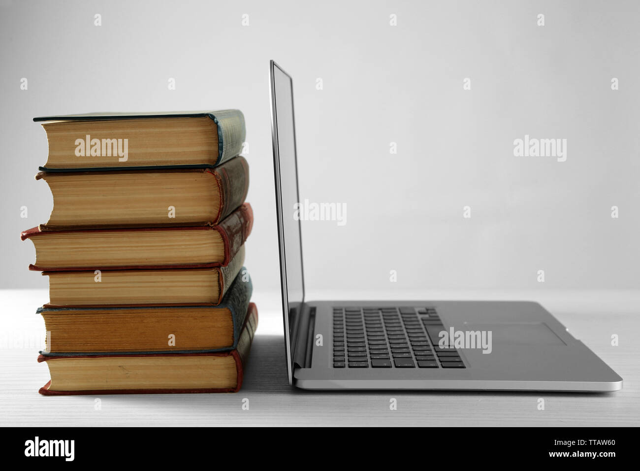 Stack of books with laptop on gray background Stock Photo - Alamy