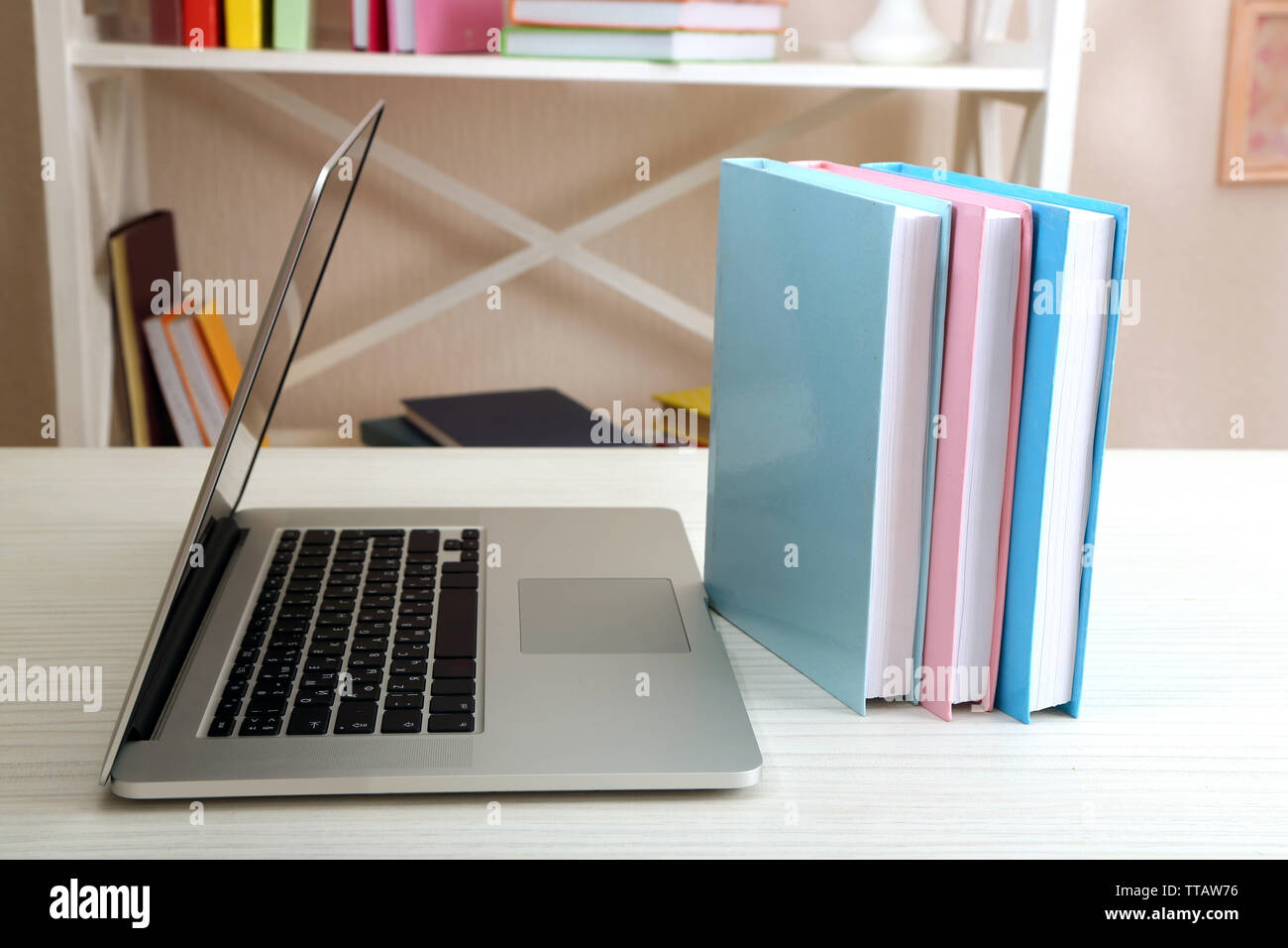 Stack of books with laptop on table in room Stock Photo - Alamy