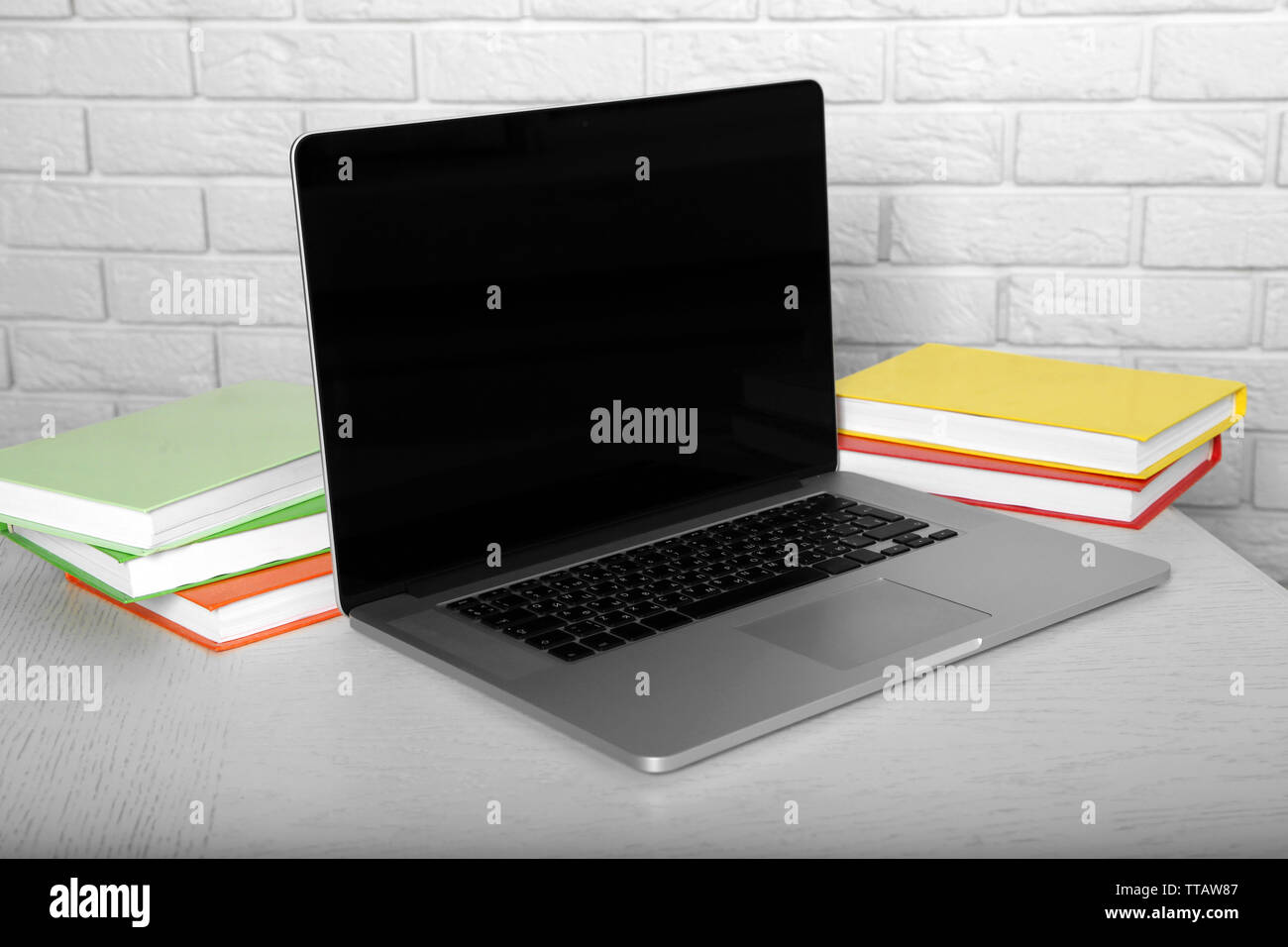 Laptop with books on brick wall background Stock Photo - Alamy