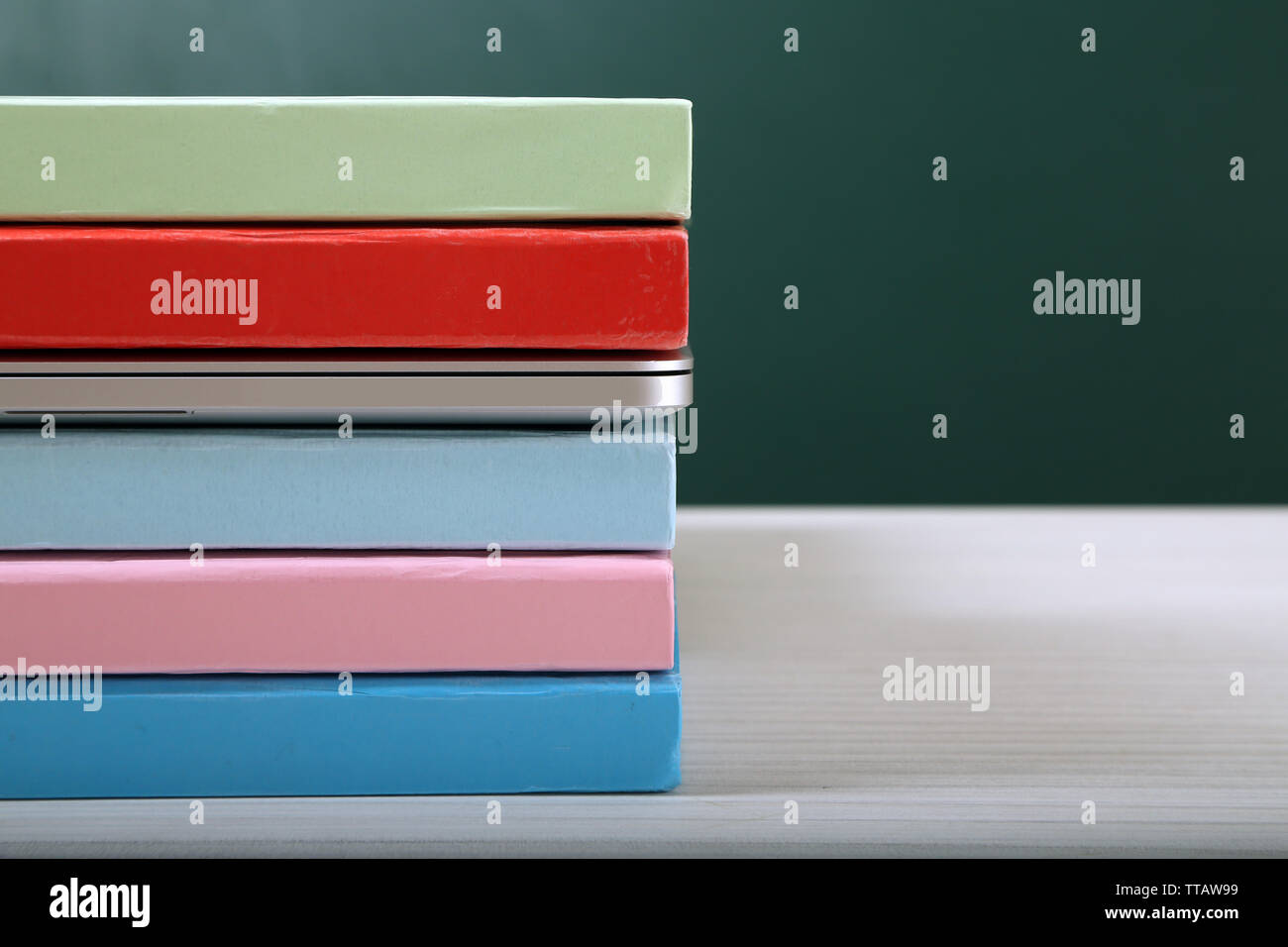 Stack of books with laptop on table in classroom Stock Photo - Alamy