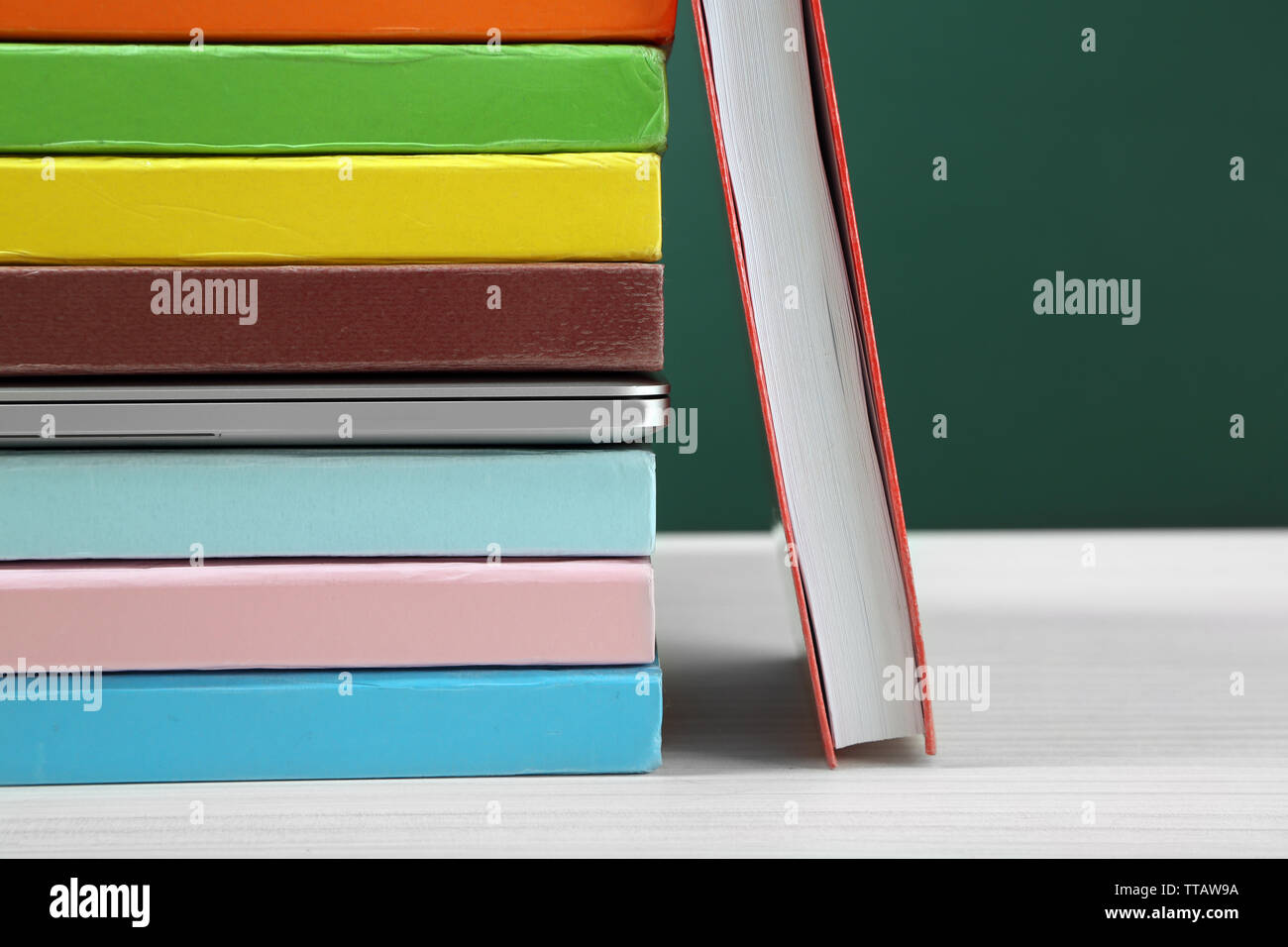 Stack of books with laptop on table in classroom Stock Photo - Alamy