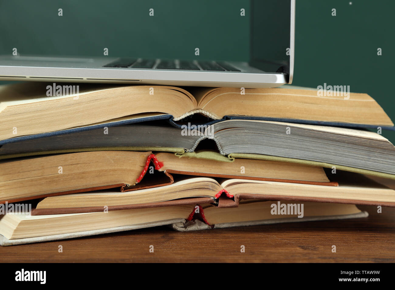 Stack of books with laptop on table in classroom Stock Photo - Alamy