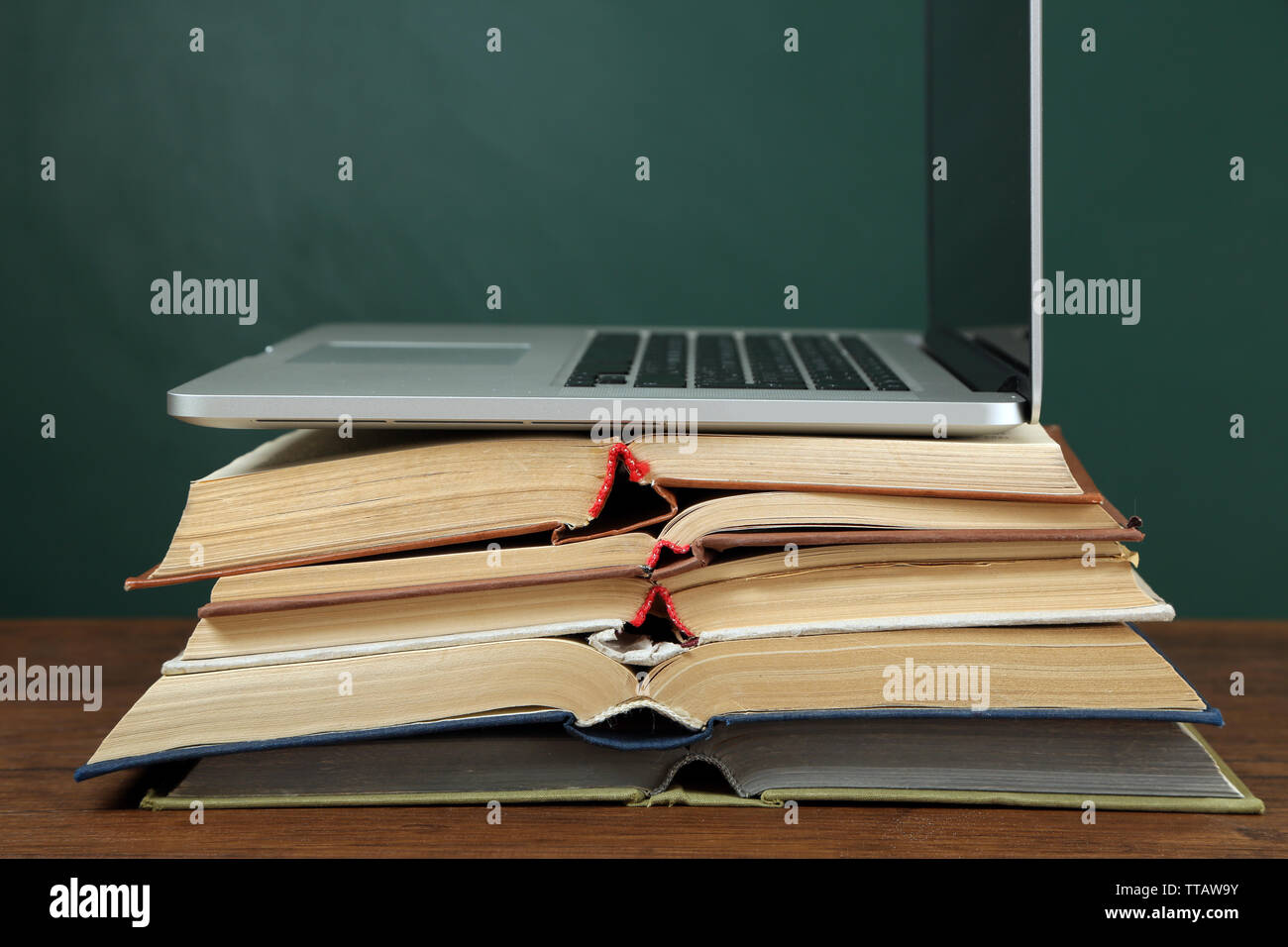Stack of books with laptop on table in classroom Stock Photo - Alamy