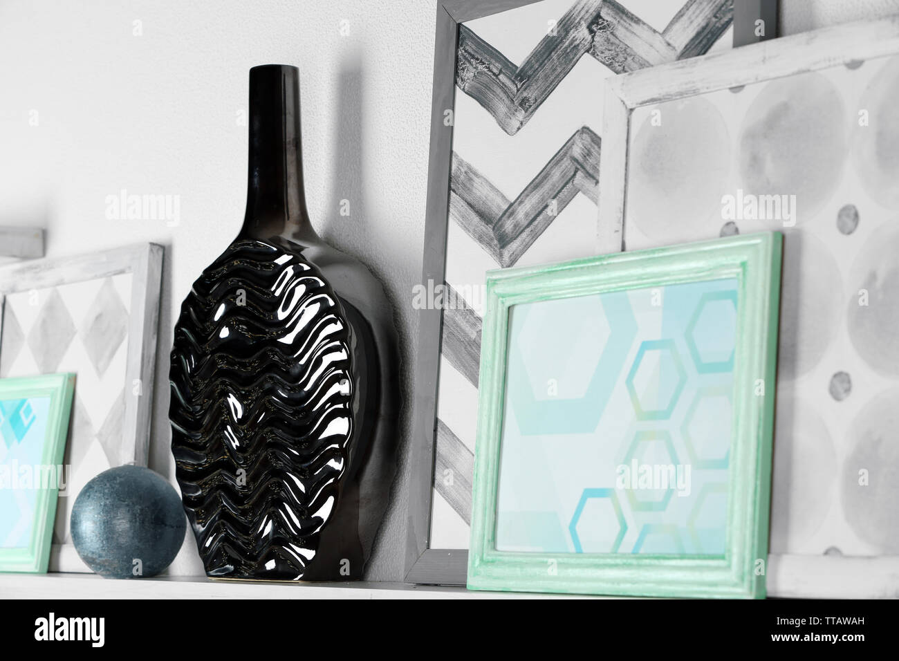 Modern vase with picture on shelf in room Stock Photo - Alamy