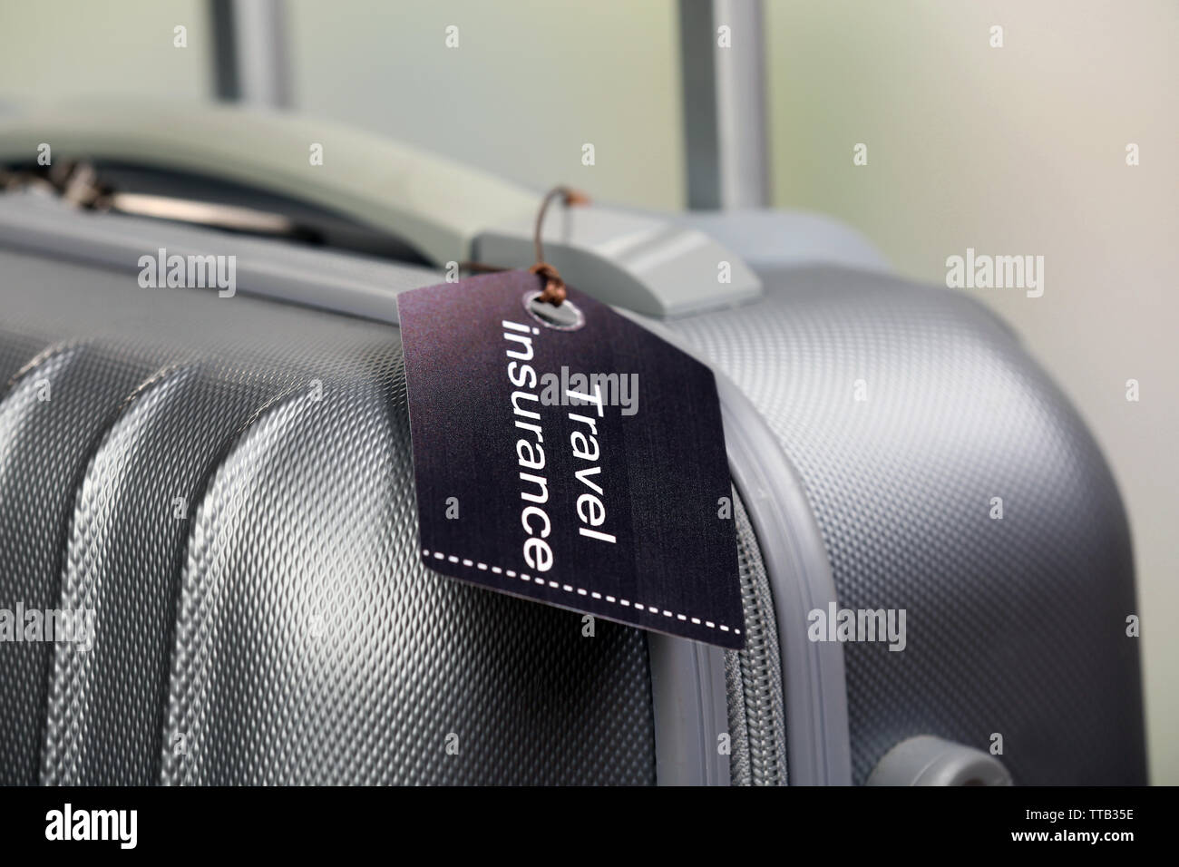 Suitcase with TRAVEL INSURANCE label on light blurred background Stock ...