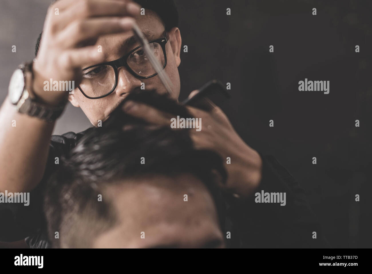 close up portrait of professional barber making hair cut of his ...