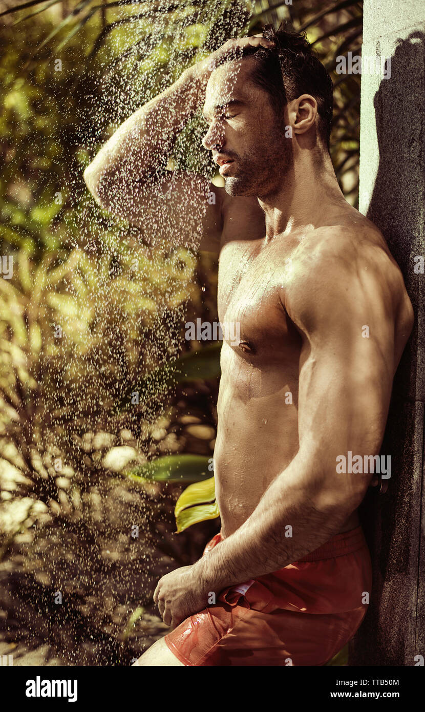 Handsome, muscular man taking a shower in the middle of the jungle Stock Photo - Alamy
