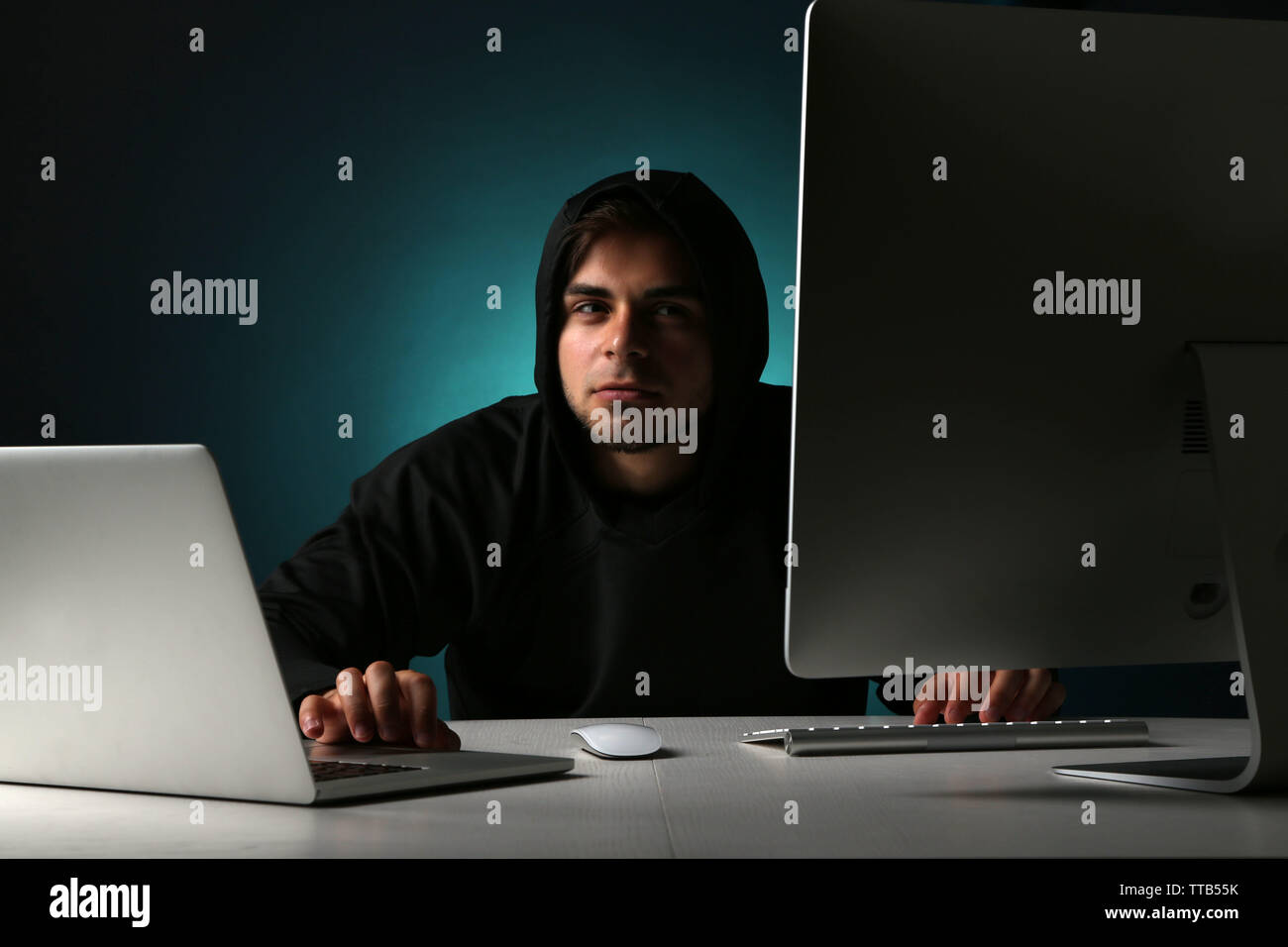 Hacker with computer and laptop on dark background Stock Photo - Alamy