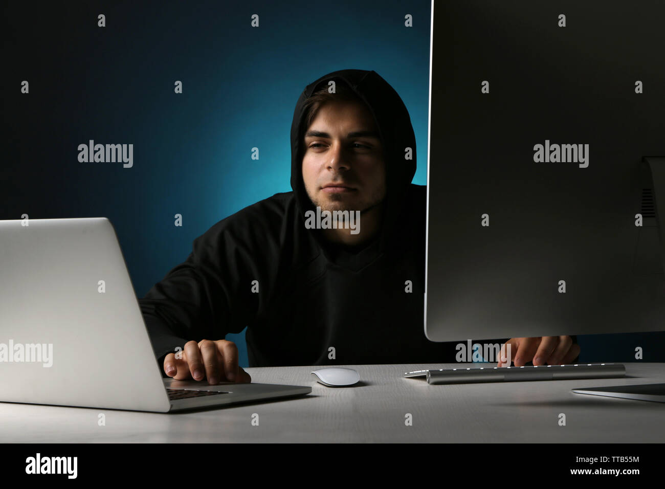 Hacker with computer and laptop on dark background Stock Photo - Alamy