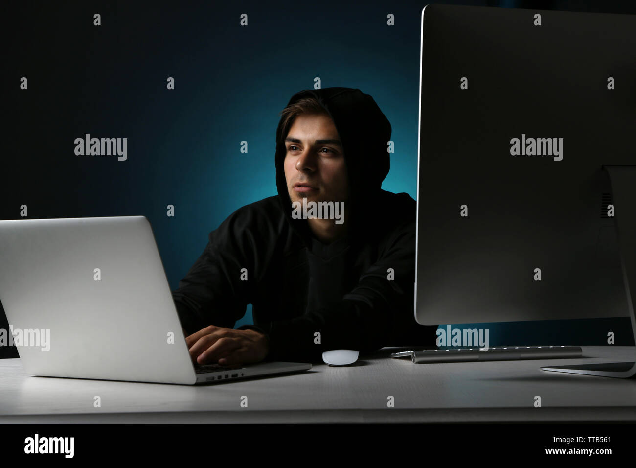 Hacker with computer and laptop on dark background Stock Photo - Alamy