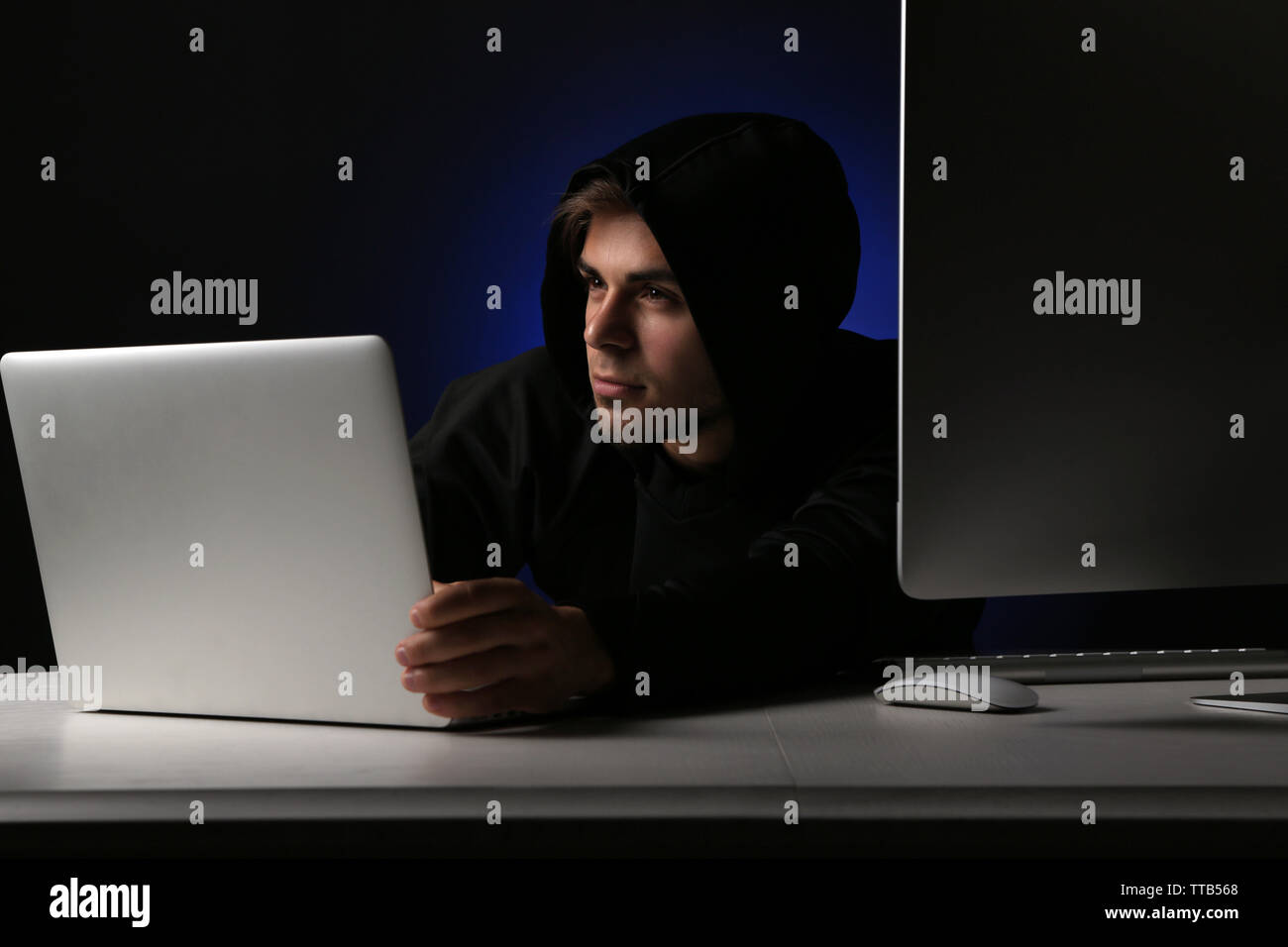 Hacker with computer and laptop on dark background Stock Photo - Alamy